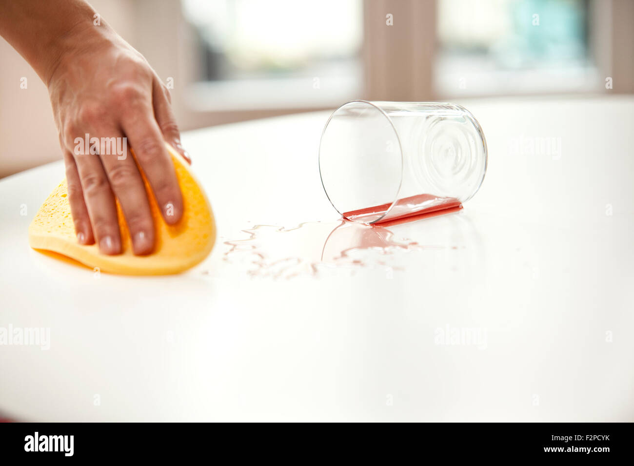 Woman wiping liquid from table from glass fallen down Stock Photo - Alamy