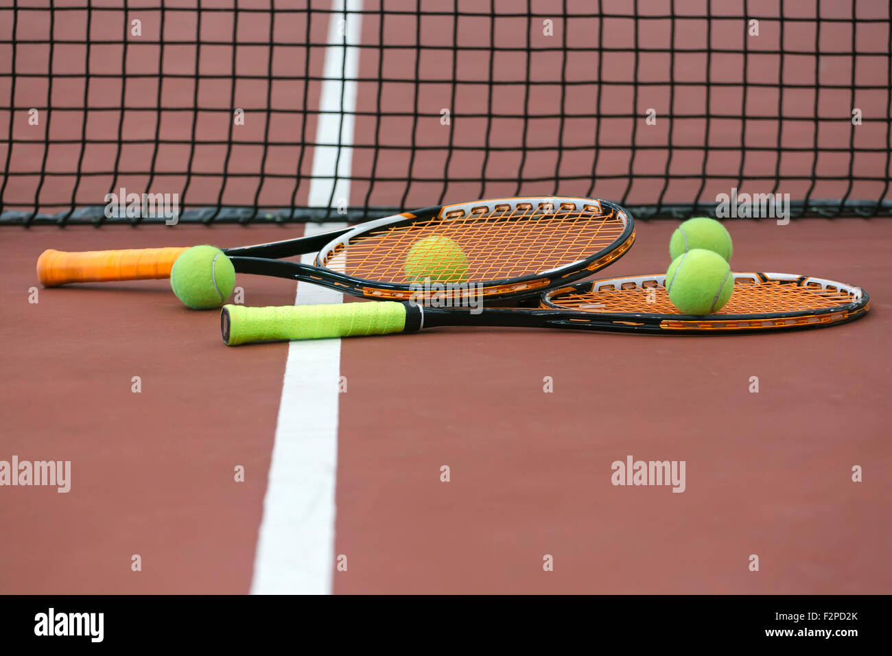 Two tennis rackets and four balls lying on ground of tennis court Stock ...