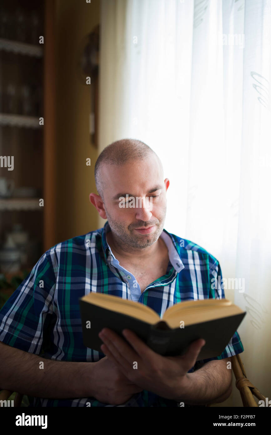 Portrait of man reading a book at home Stock Photo - Alamy