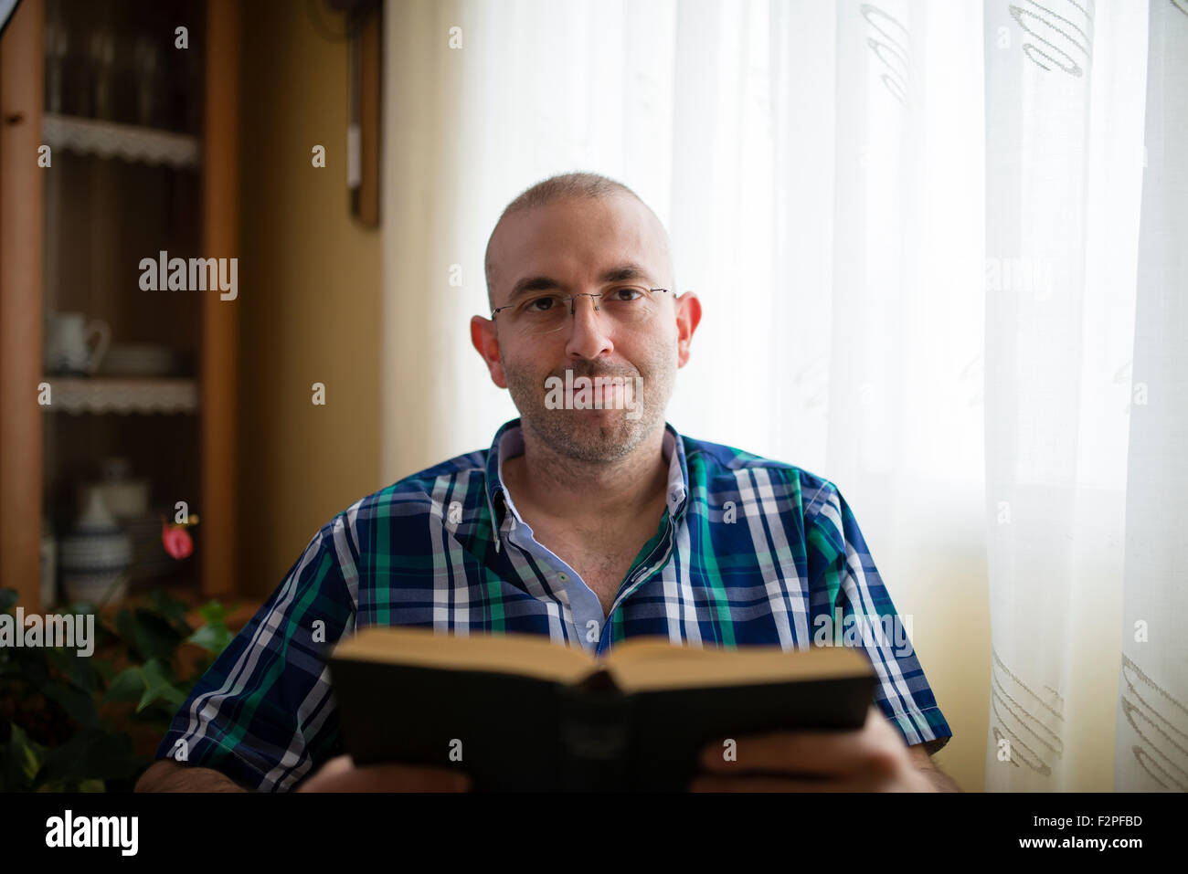Portrait of man with book at home Stock Photo - Alamy