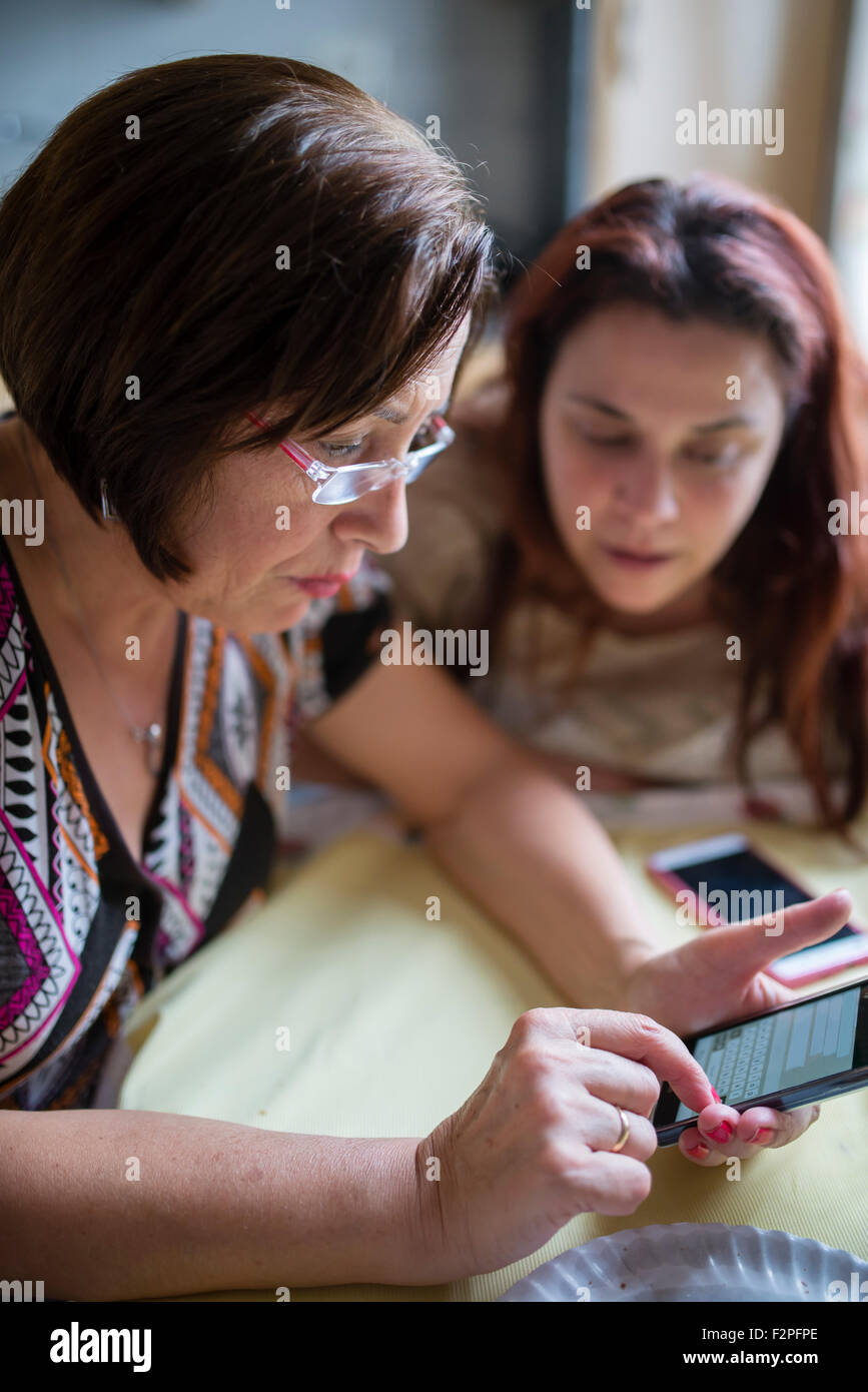 Woman helping senior woman how to use a smartphone Stock Photo - Alamy