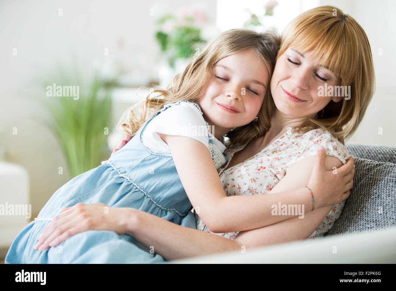 Mother and daughter sitting on couch, cuddling Stock Photo - Alamy