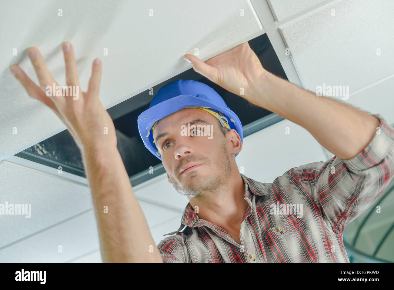 Builder replacing ceiling panel Stock Photo - Alamy