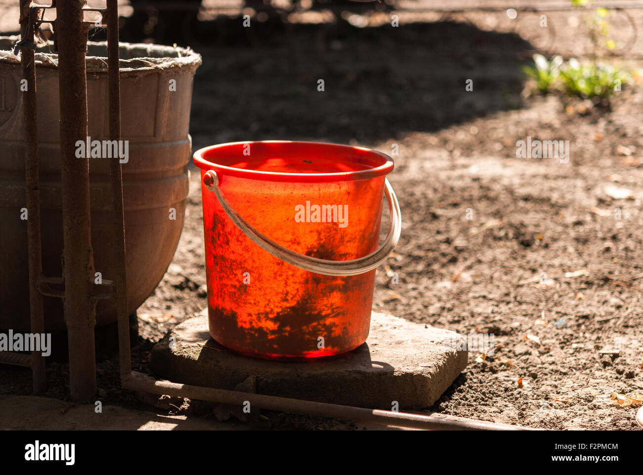 Old red dirty housework plastic bucket on the village yard with the ...