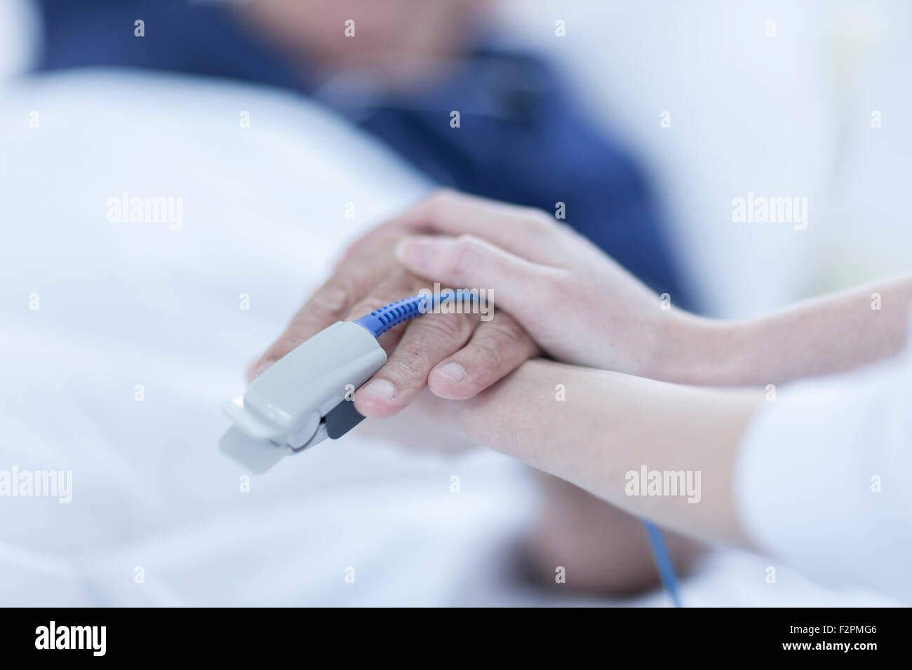 Finger heart monitor on patient, nurse holding hands Stock Photo - Alamy