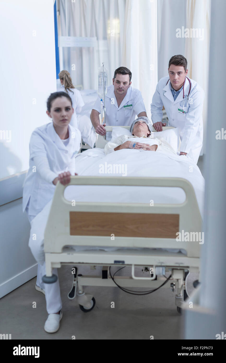 Hospital staff pushing bed with patient on floor Stock Photo - Alamy