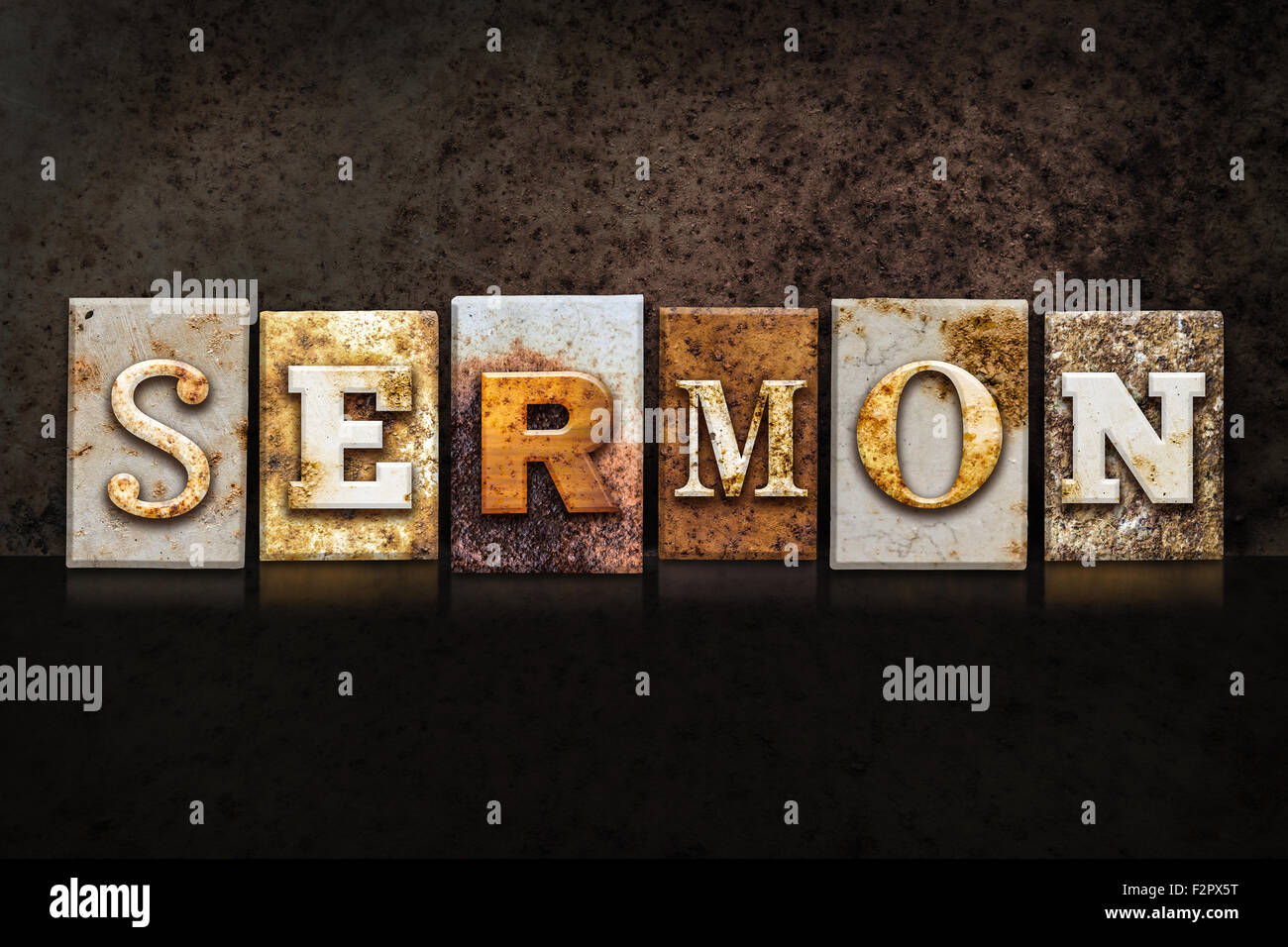 The word "SERMON" written in rusty metal letterpress type on a dark ...