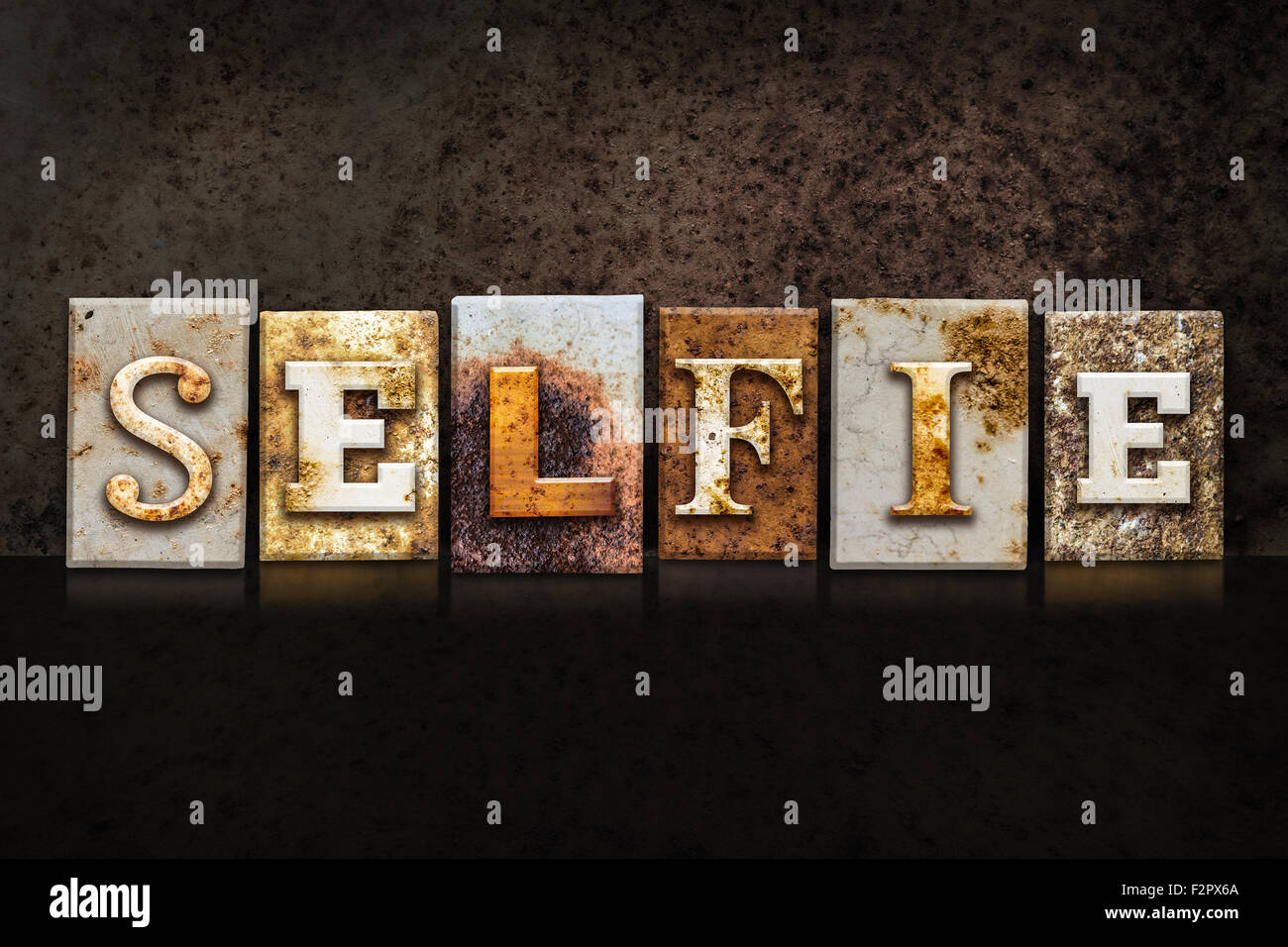 The word "SELFIE" written in rusty metal letterpress type on a dark ...