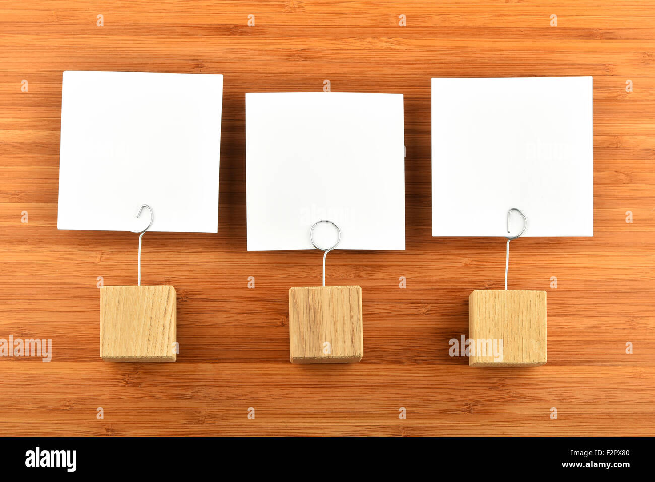 Three white paper notes with wooden holders on bamboo wooden background ...