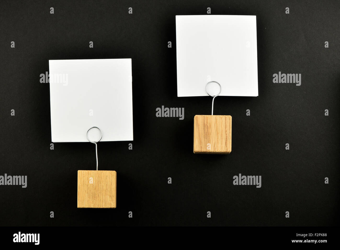 Two white paper notes at different levels with wooden holders isolated ...