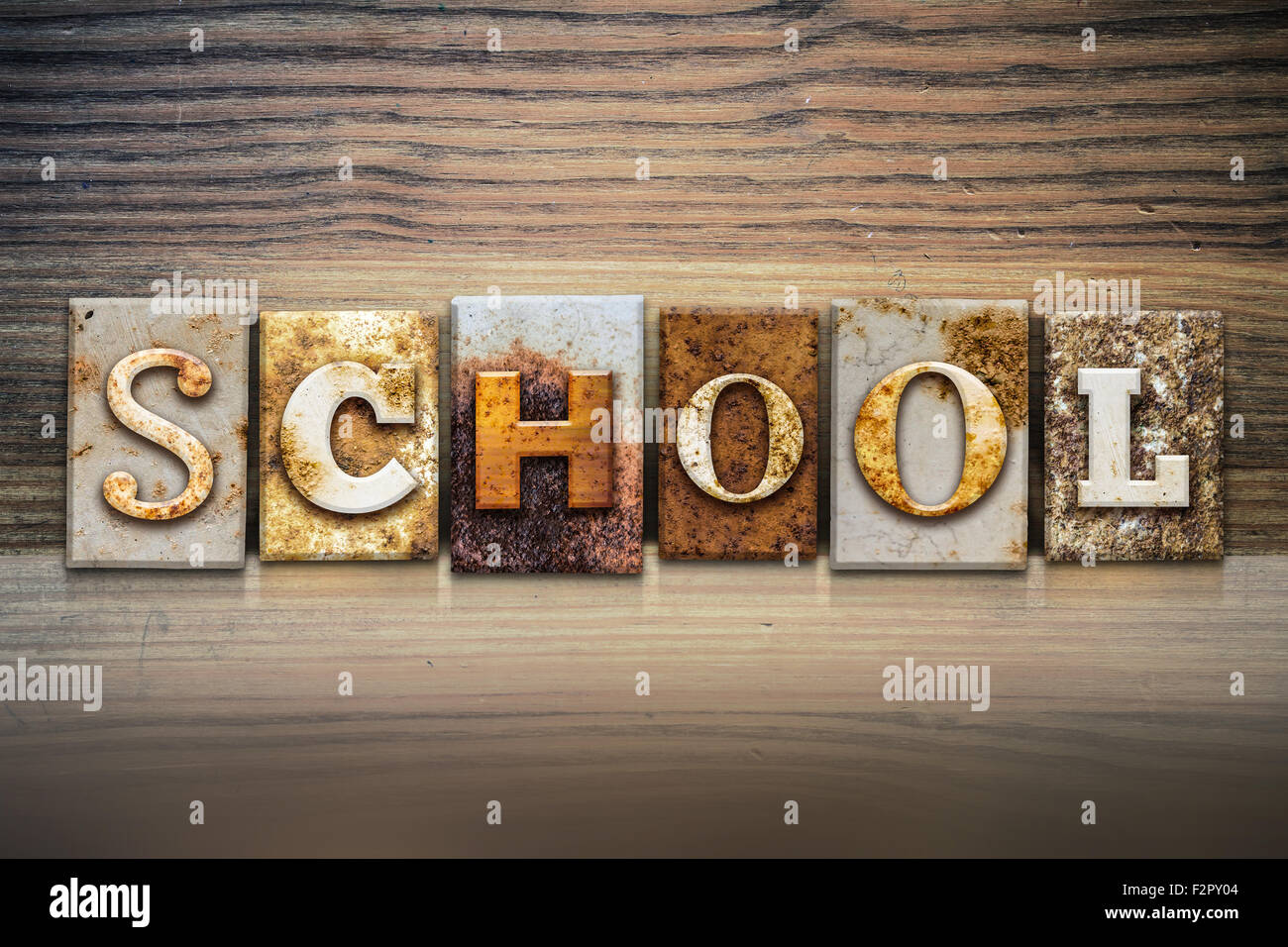 The word "SCHOOL" written in rusty metal letterpress type sitting on a ...