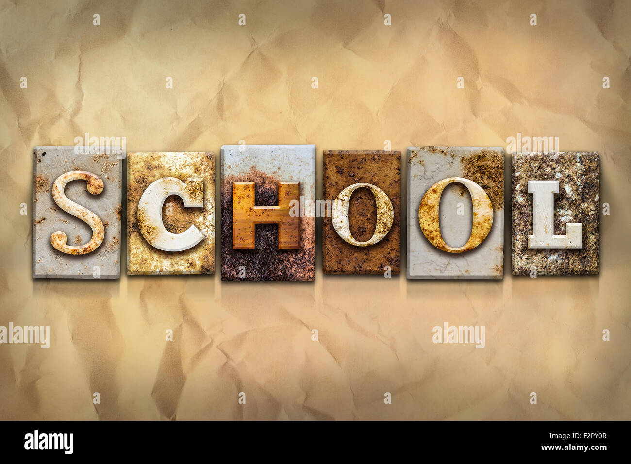 The word "SCHOOL" written in rusty metal letterpress type on a crumbled ...