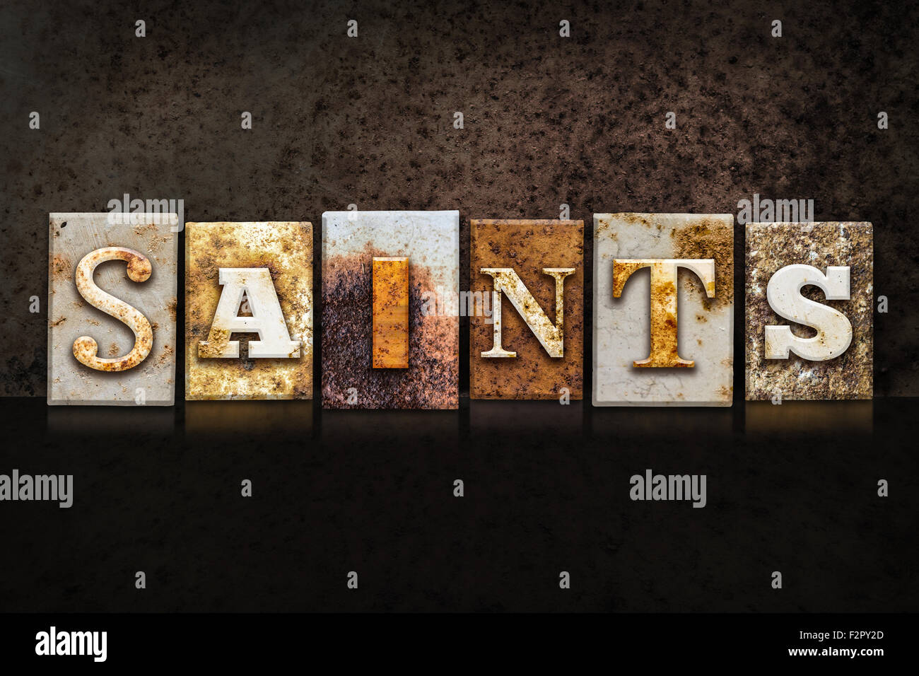 The word "SAINTS" written in rusty metal letterpress type on a dark ...