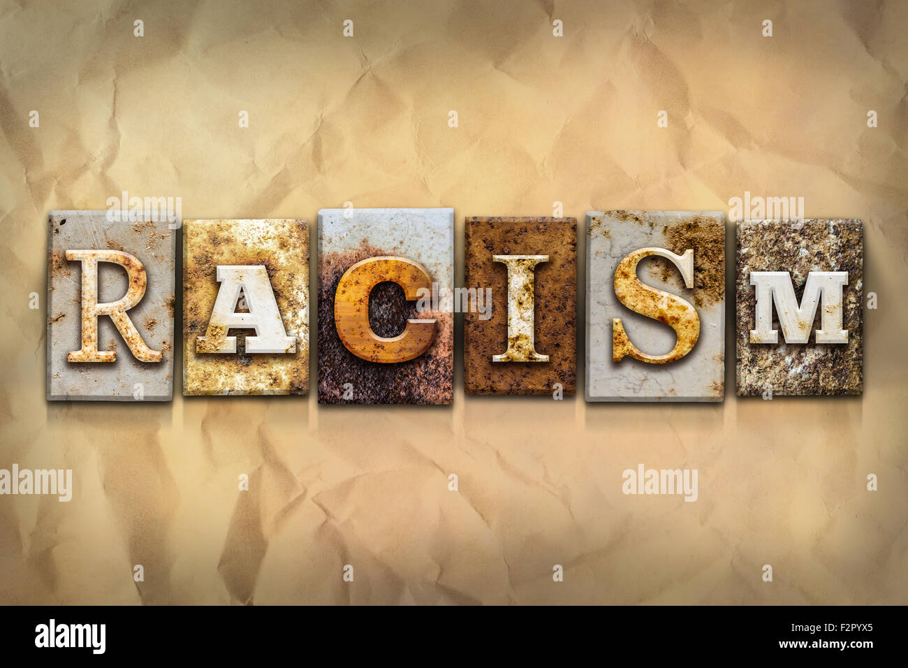 The word "RACISM" written in rusty metal letterpress type on a crumbled ...