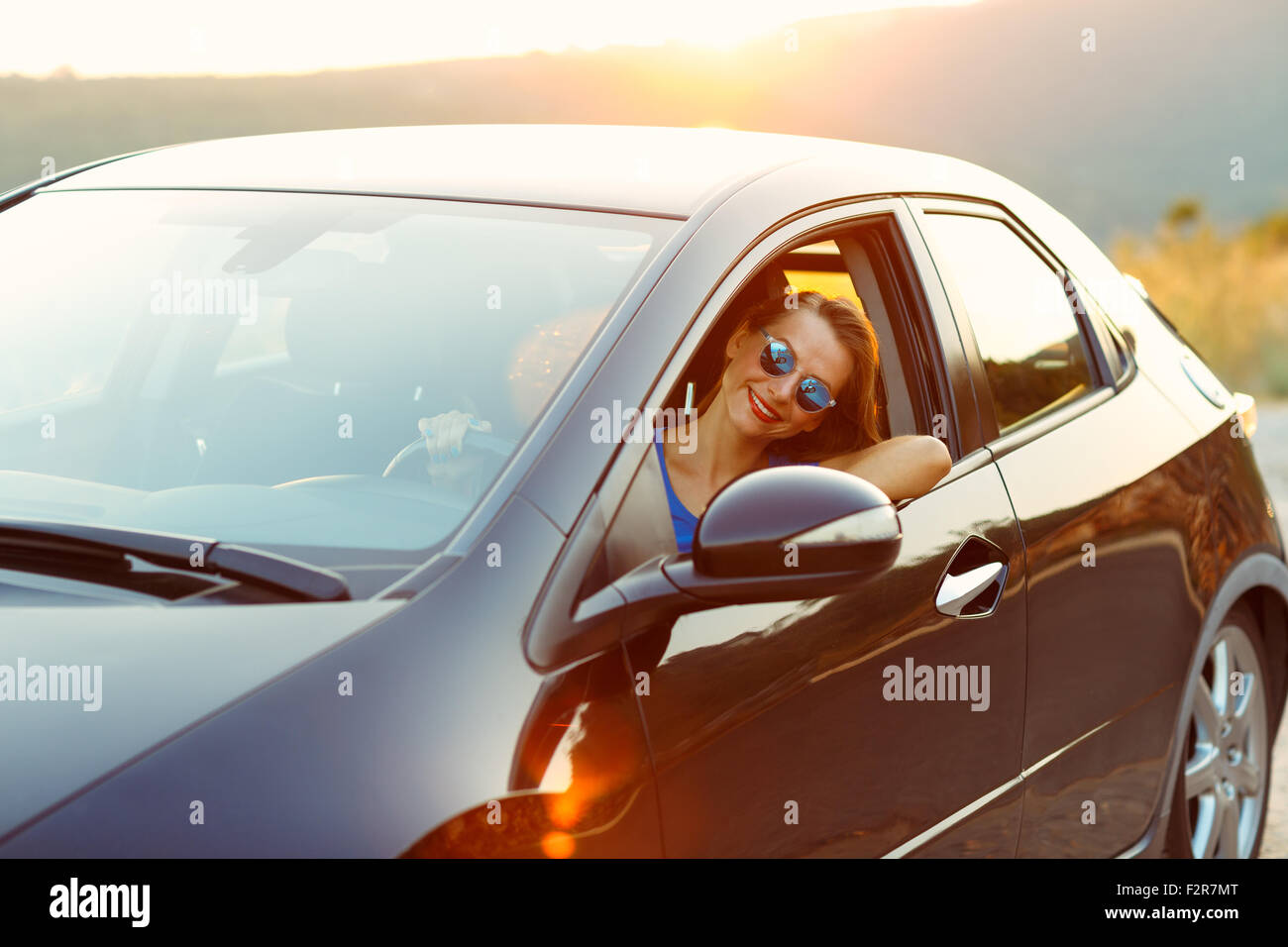 Smiling woman driving a car at sunset. Travel concept Stock Photo - Alamy