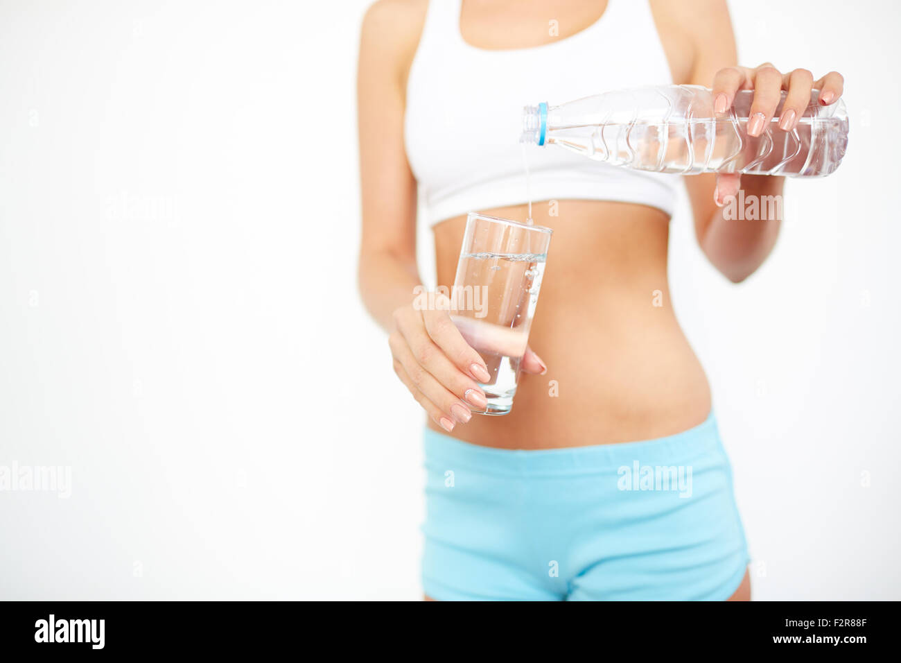 Fit woman pouring mineral water from bottle into glass Stock Photo - Alamy