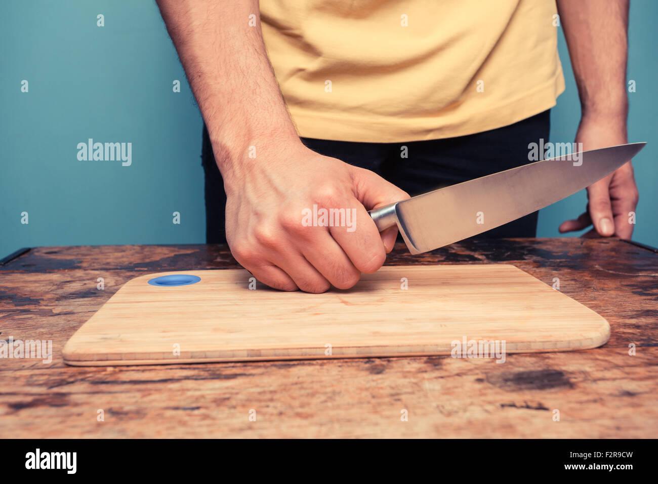 Young man at table with chopping board and knife Stock Photo - Alamy