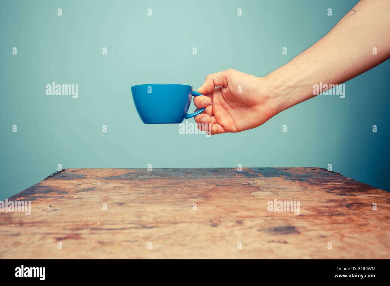Young man placing coffee cup on table Stock Photo - Alamy