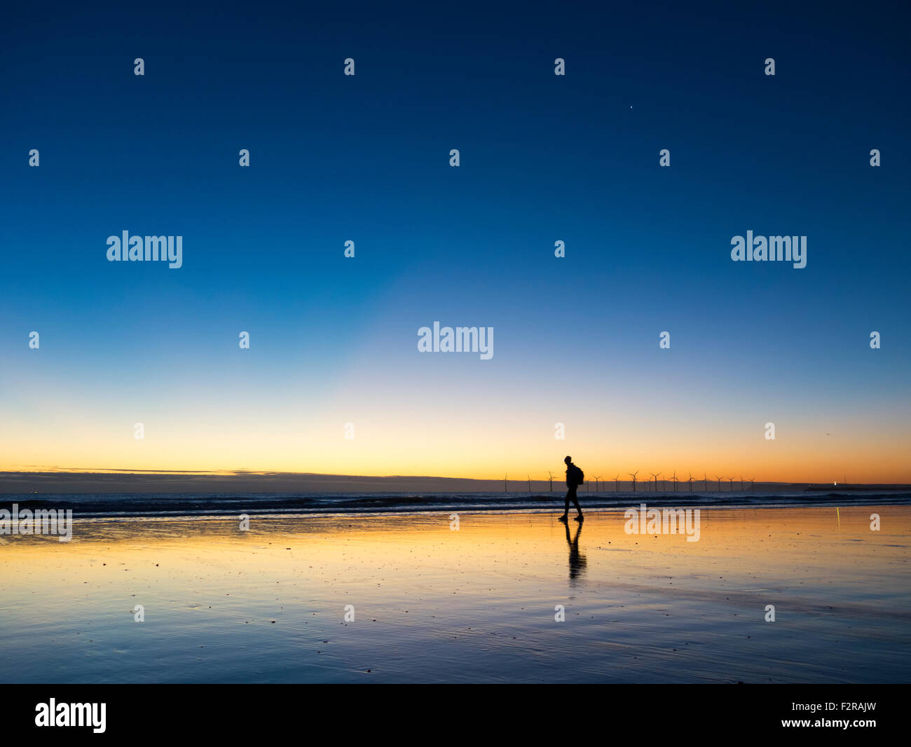 A walker on Seaton Carew beach at sunrise, setting out on the 55km ...