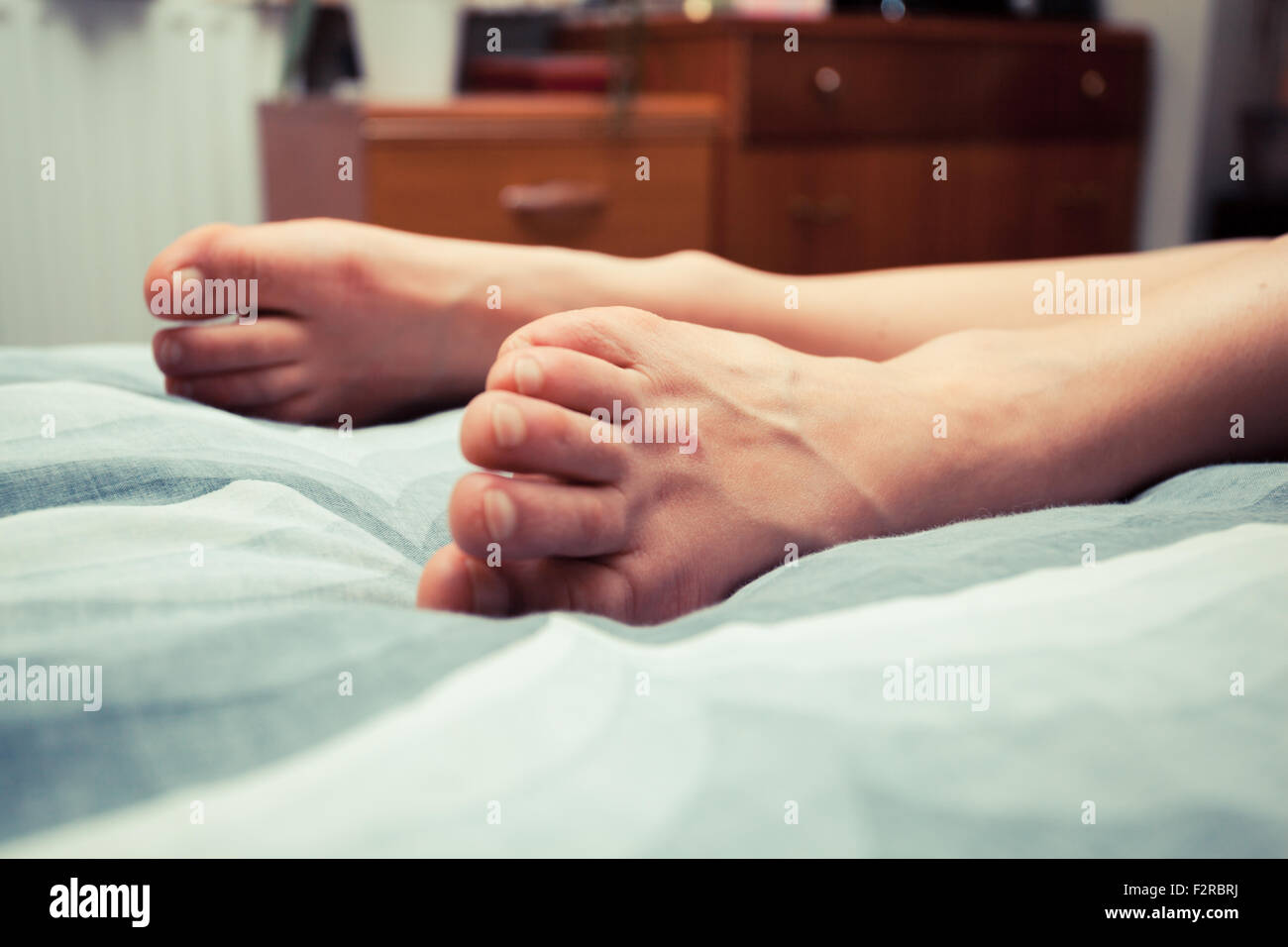 the feet of a young woman on the bedsheets in a domestic setting Stock ...
