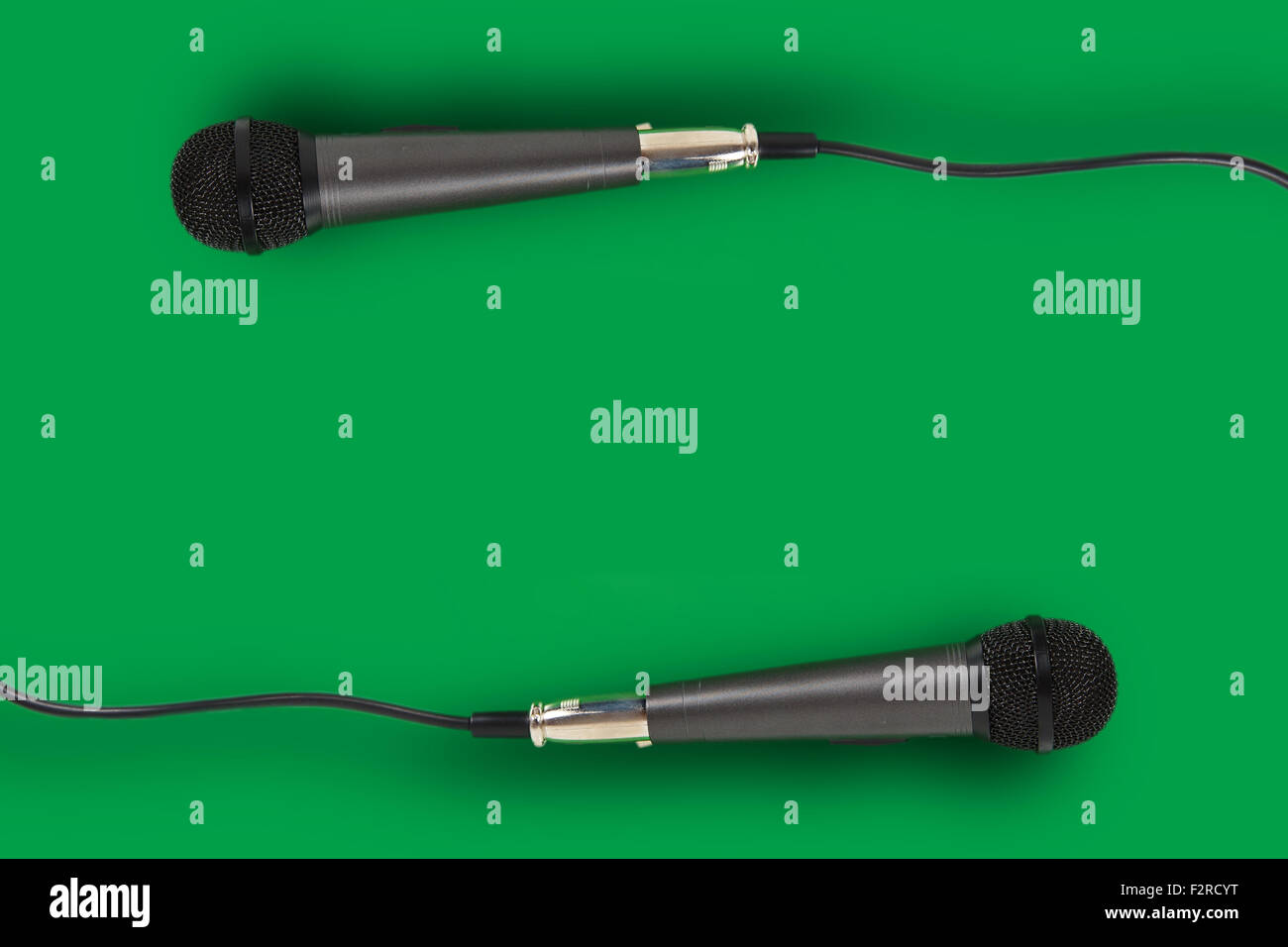 Two black microphones isolated on a green background Stock Photo - Alamy