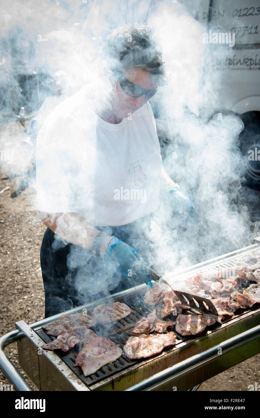A woman cooking bacon on a barbeque grill surrounded by smoke Stock ...