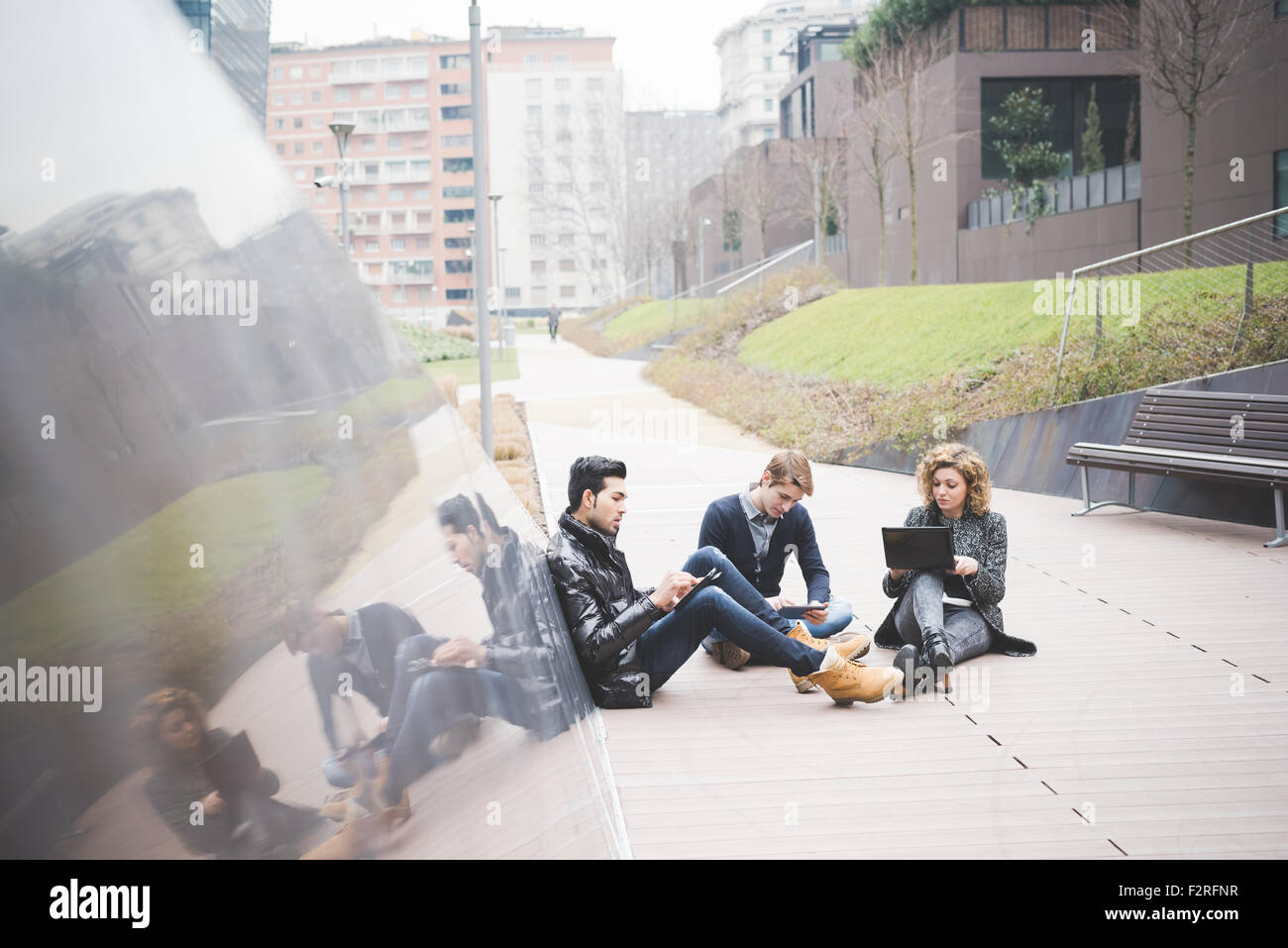 Multiracial business people working outdoor in town sitting on the ...