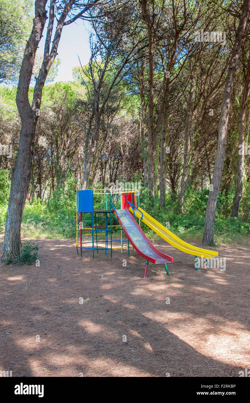 Playground with colored slide in a green pine forest Stock Photo - Alamy