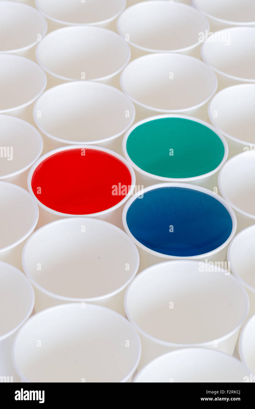 White paper cups on a white background. Some cups have colored liquid ...