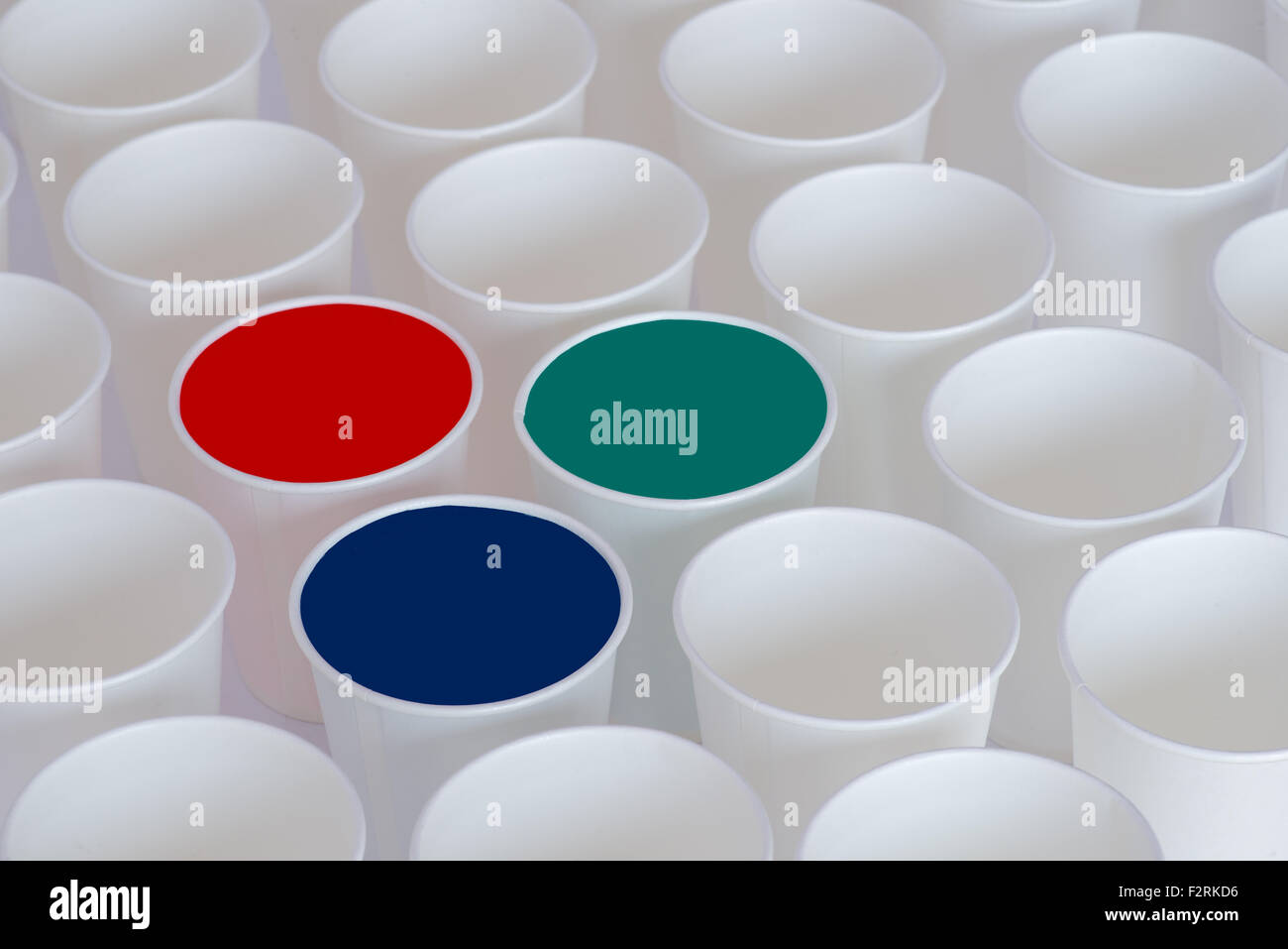 White paper cups on a white background. Some cups have colored liquid ...