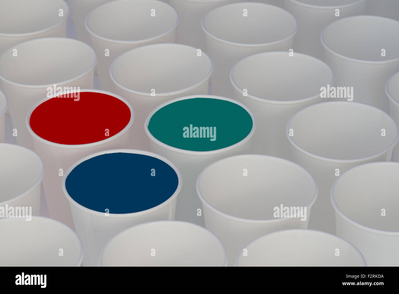 White paper cups on a white background. Some cups have colored liquid ...