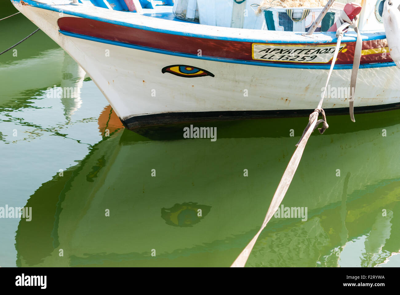 Bow of old wooden fishing boat with "evil eye" decor with reflection in ...