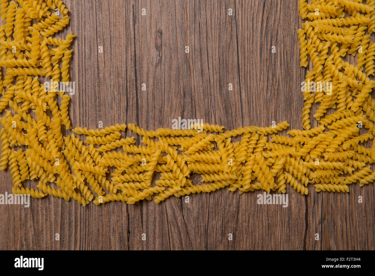 Uncooked italian pasta, brown wood table background Stock Photo - Alamy