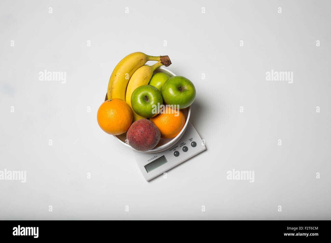 fruit on weighing scales against a white background Stock Photo - Alamy
