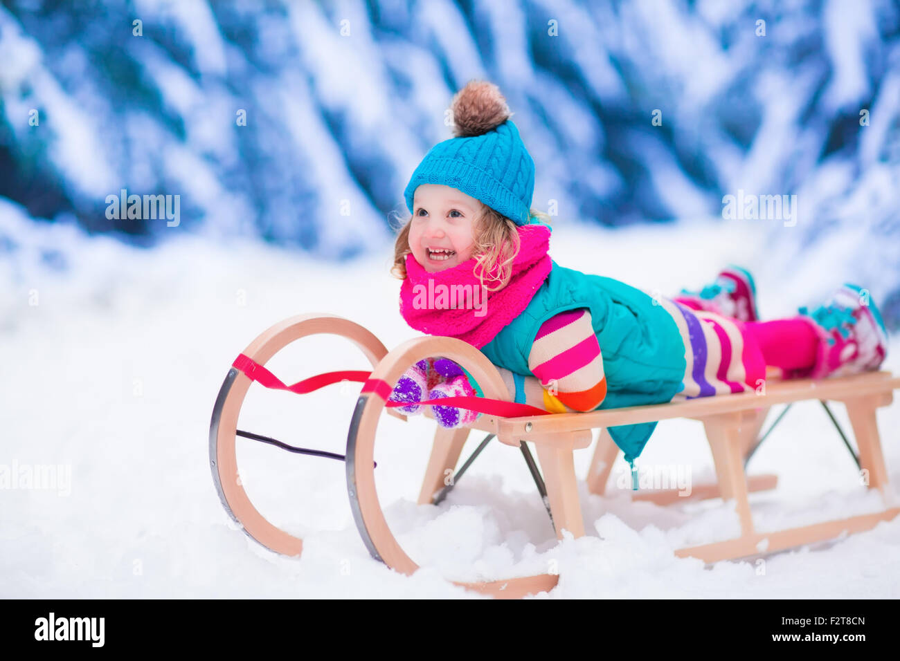 Little girl enjoying a sleigh ride. Child sledding. Toddler kid riding ...