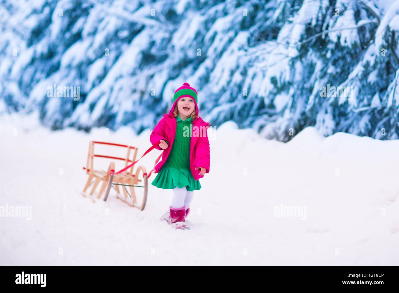 Little girl enjoying a sleigh ride. Child sledding. Toddler kid riding a sledge. Children play ...