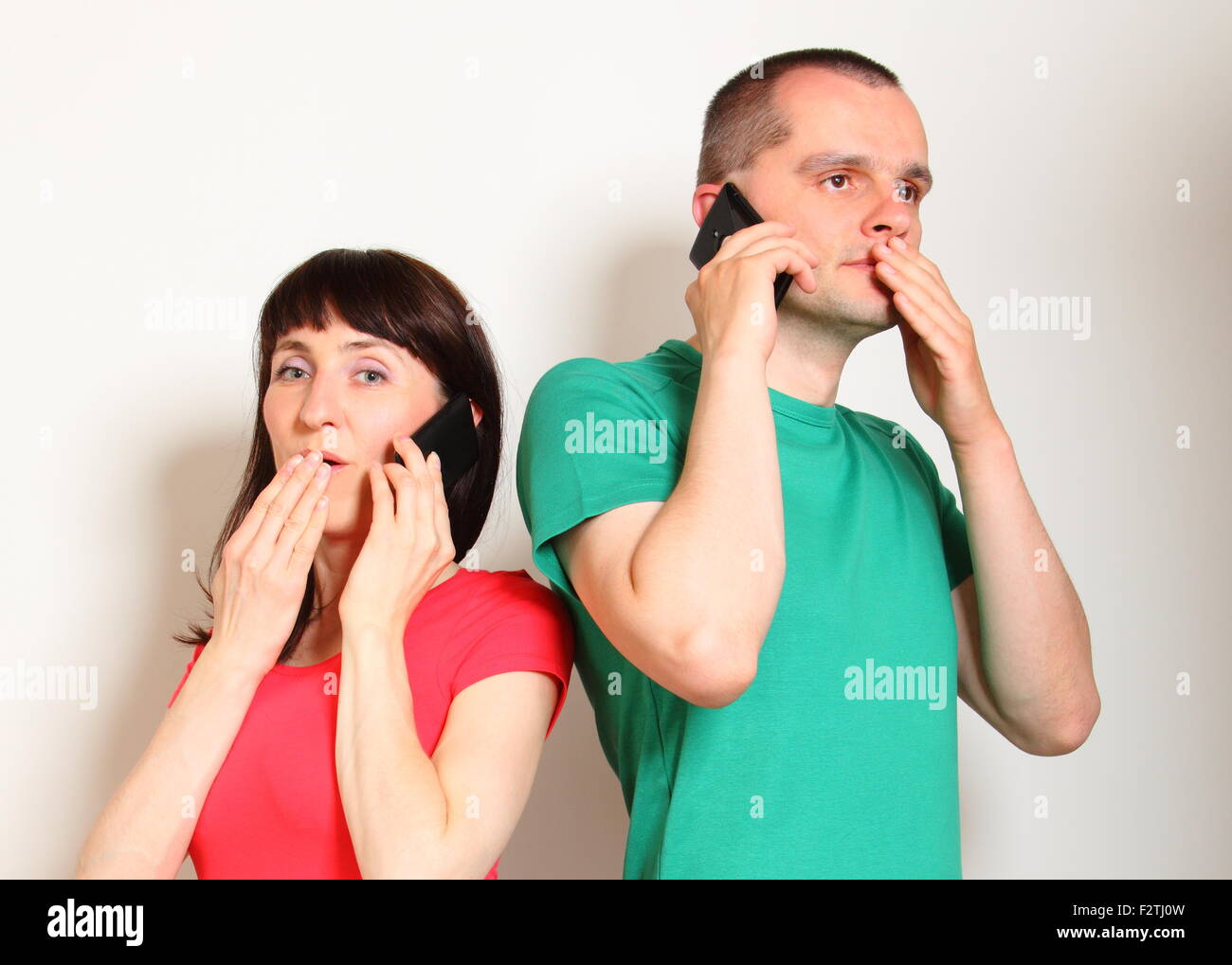 Shocked woman and man receive an unexpected message while talking on ...