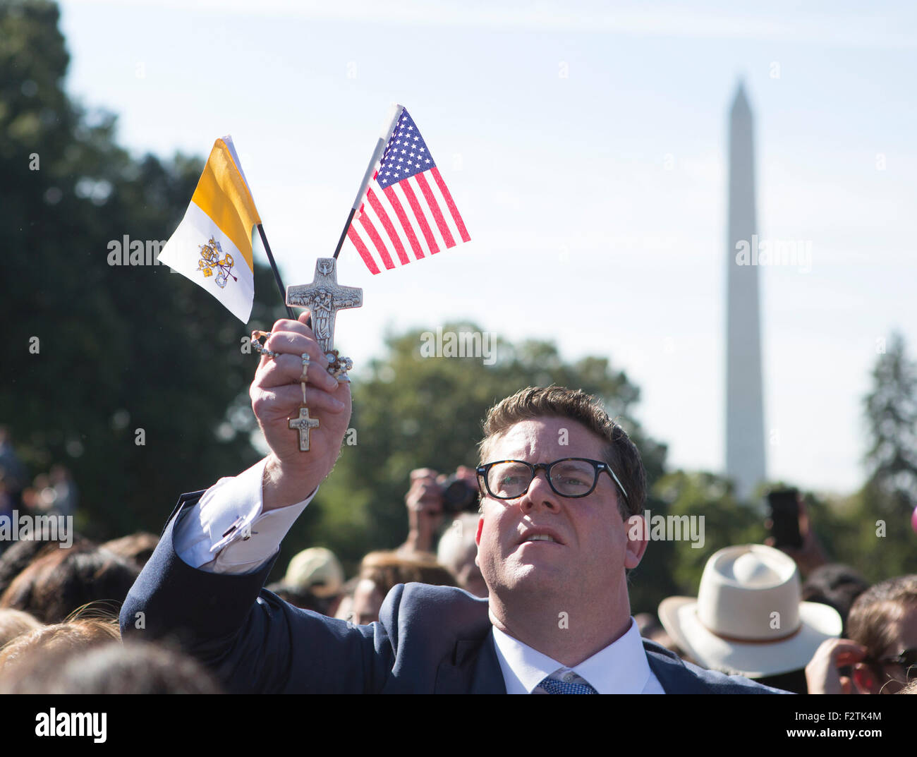 A man holds the US and Papal flags along with a crucifix and a rosary ...
