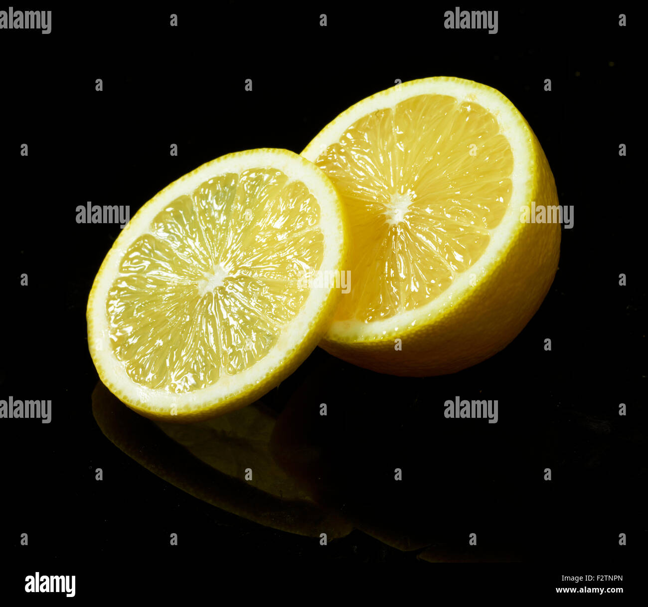 Lemon (Citrus limon), slice, sliced in half, against a black background ...