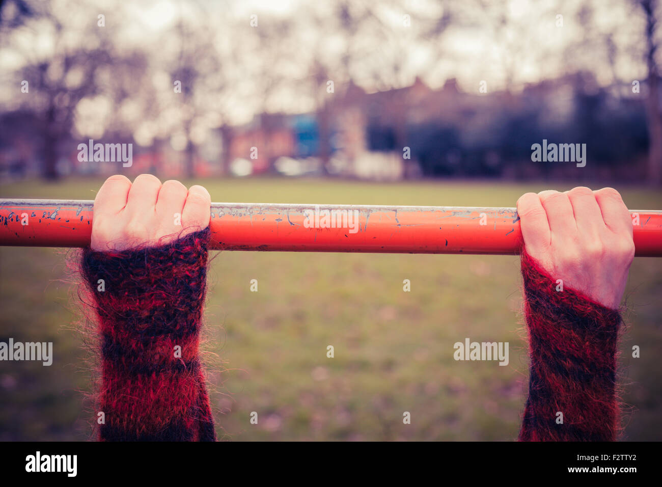 Closeup on a young woman's hands as she is hanging from a monkey bar in ...