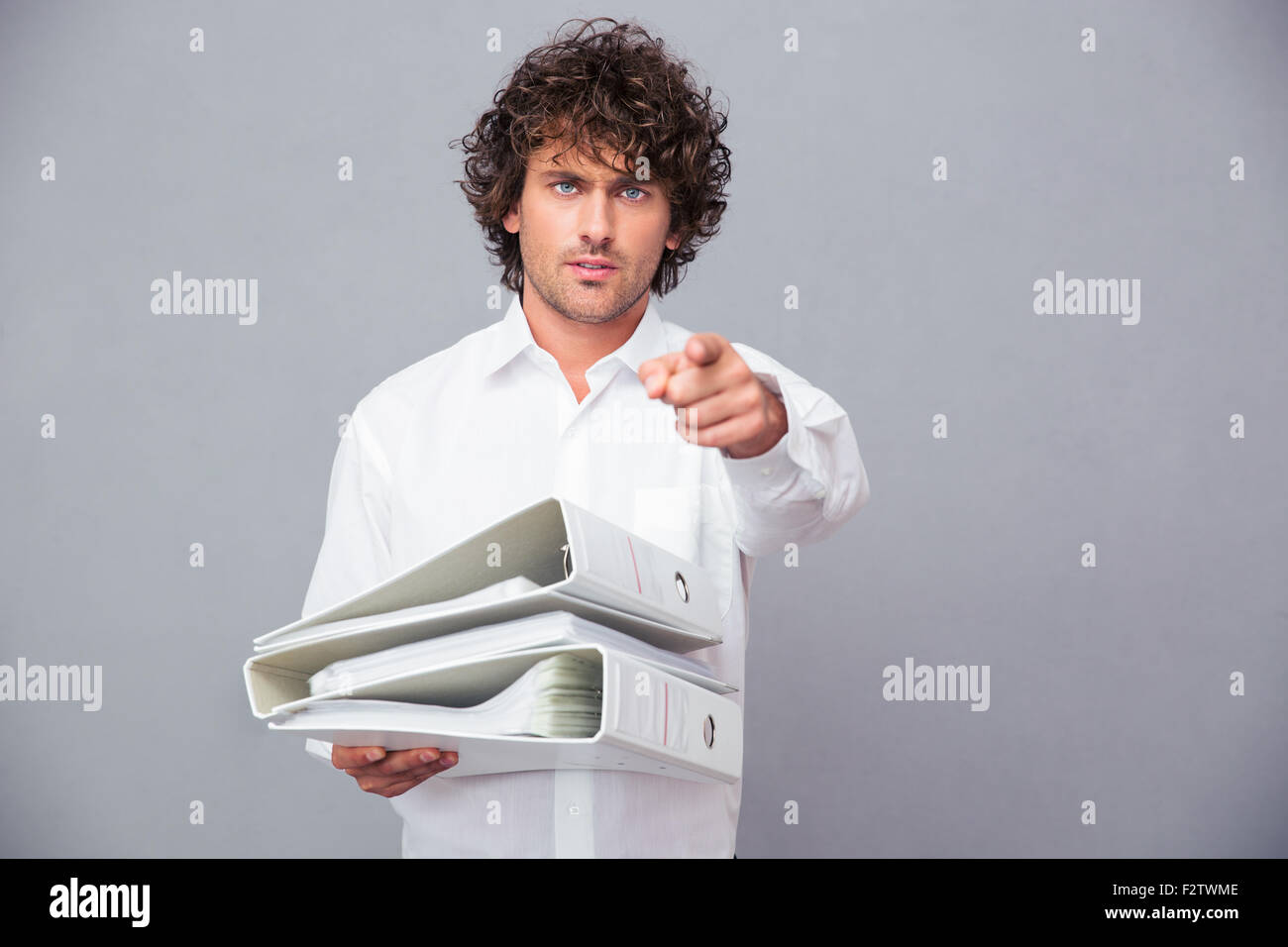 Portrait of a handsome businessman holding folder and pointing finger ...