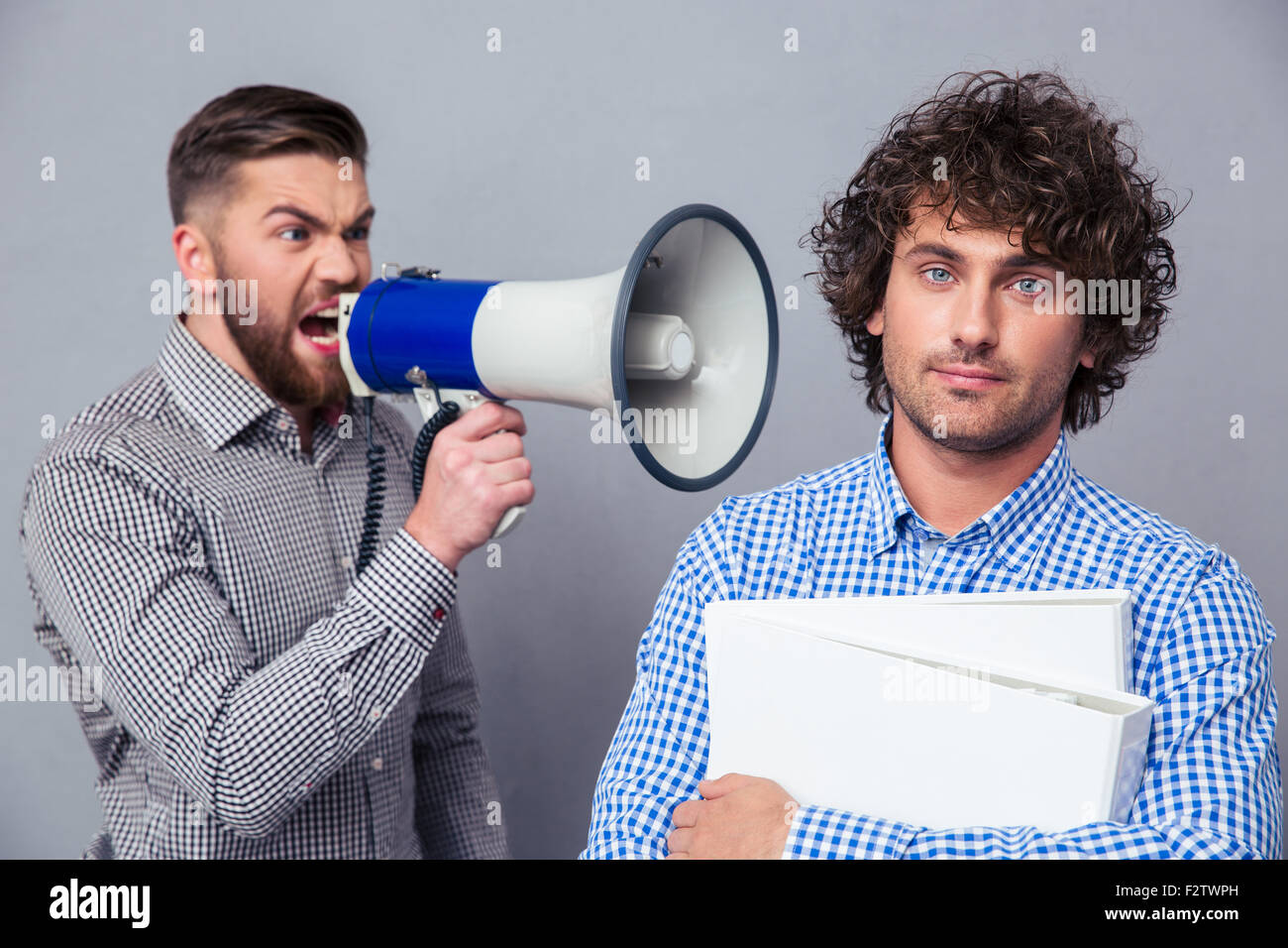 Angry businessman yelling via megaphone to another man over gray ...