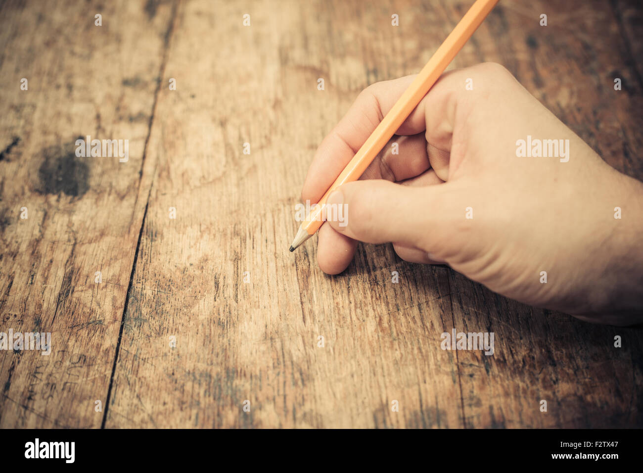 A man's hand is writing on a table with a pencil Stock Photo - Alamy