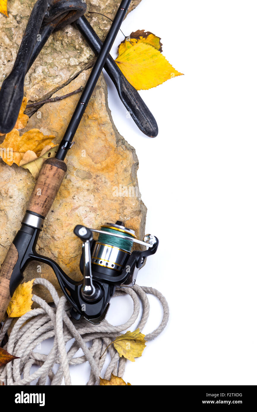 fishing rods with reel on stones with anchor and leafs on white ...