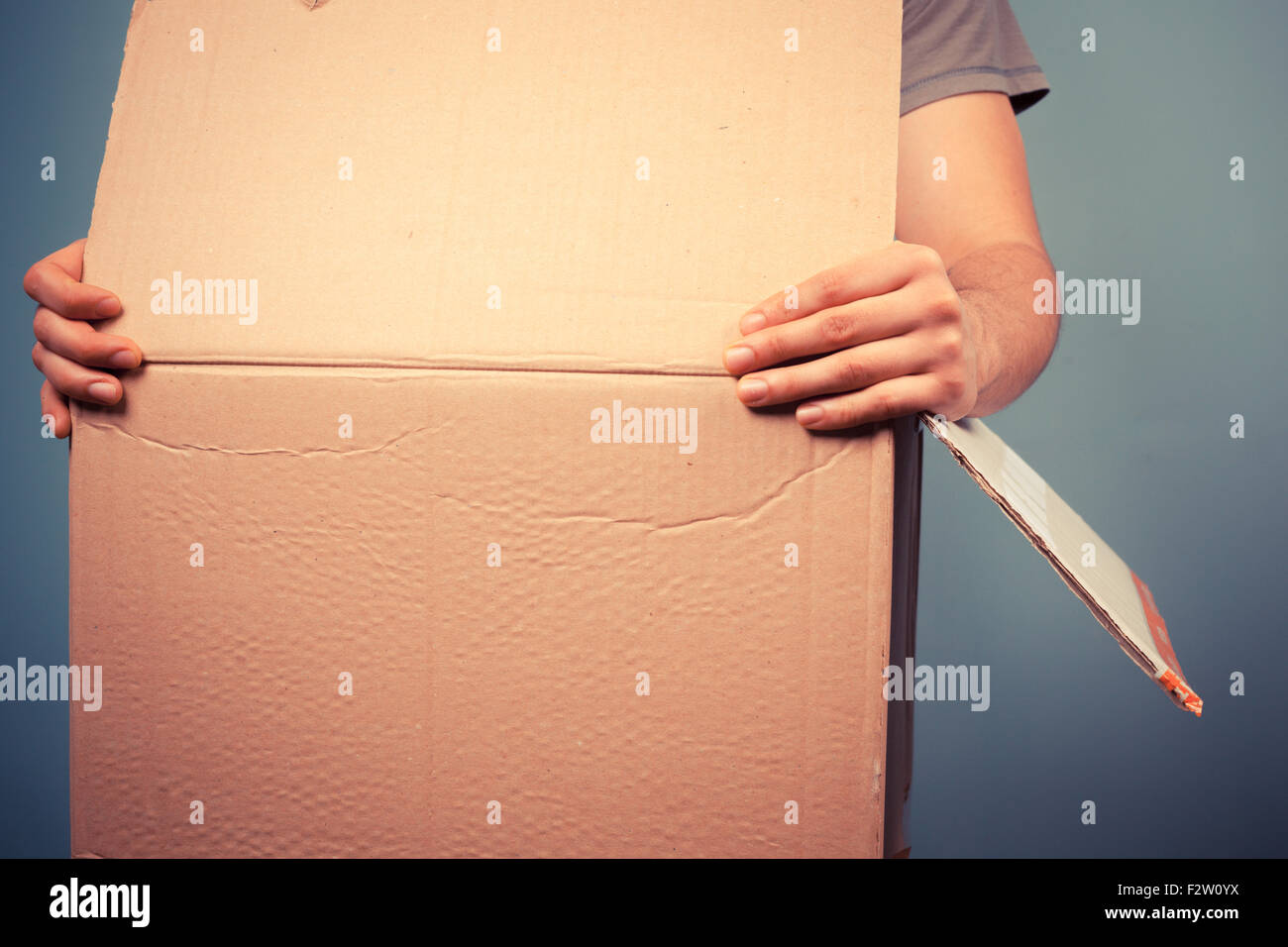Young man is moving house and is holding a large cardboard box Stock ...