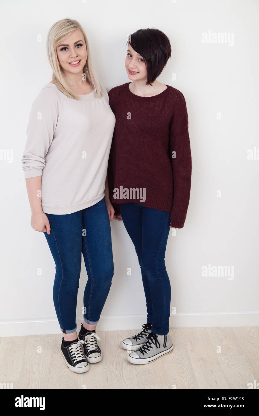 Two sisters standing together against an inside wall Stock Photo - Alamy
