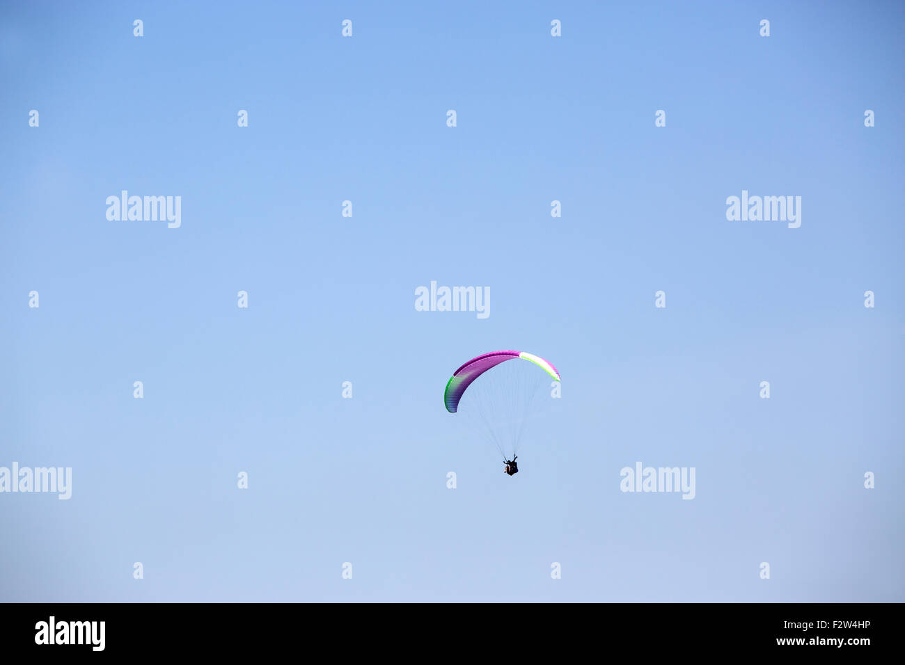 Colorful paraglider flying in a blue sky Stock Photo - Alamy