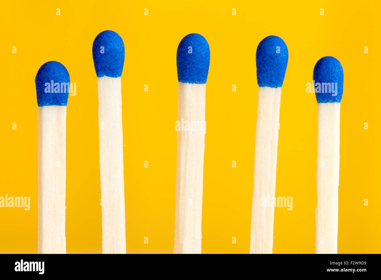 Row of five matchsticks on yellow background Stock Photo - Alamy