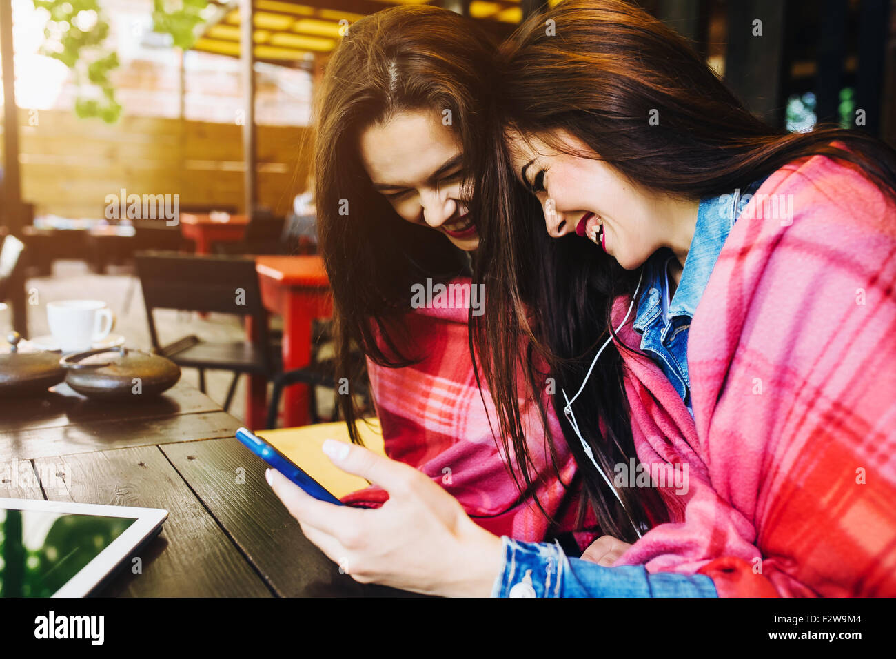 Two girl sitting listening music Stock Photo - Alamy