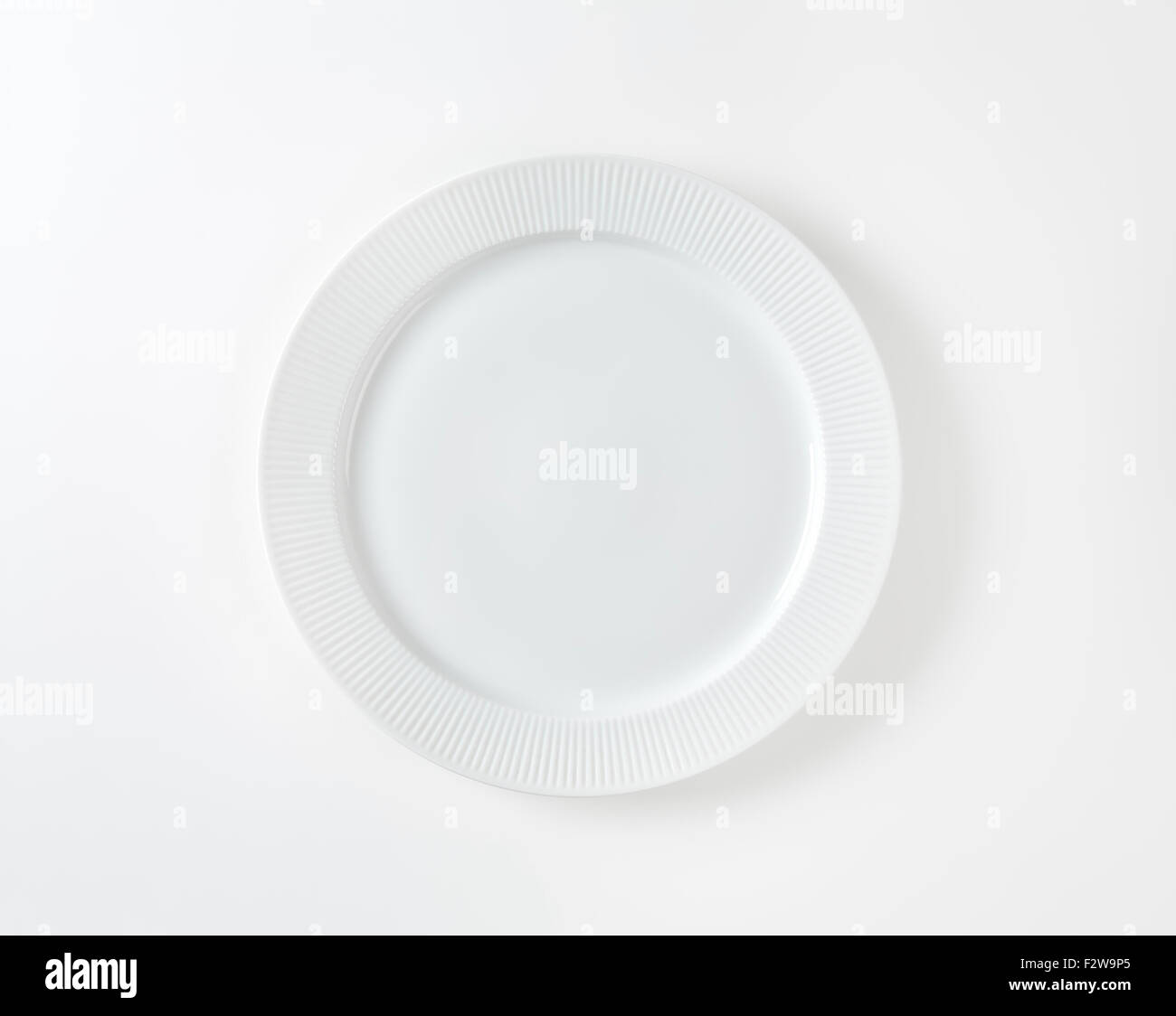 white plate with fluted rim on white background Stock Photo - Alamy